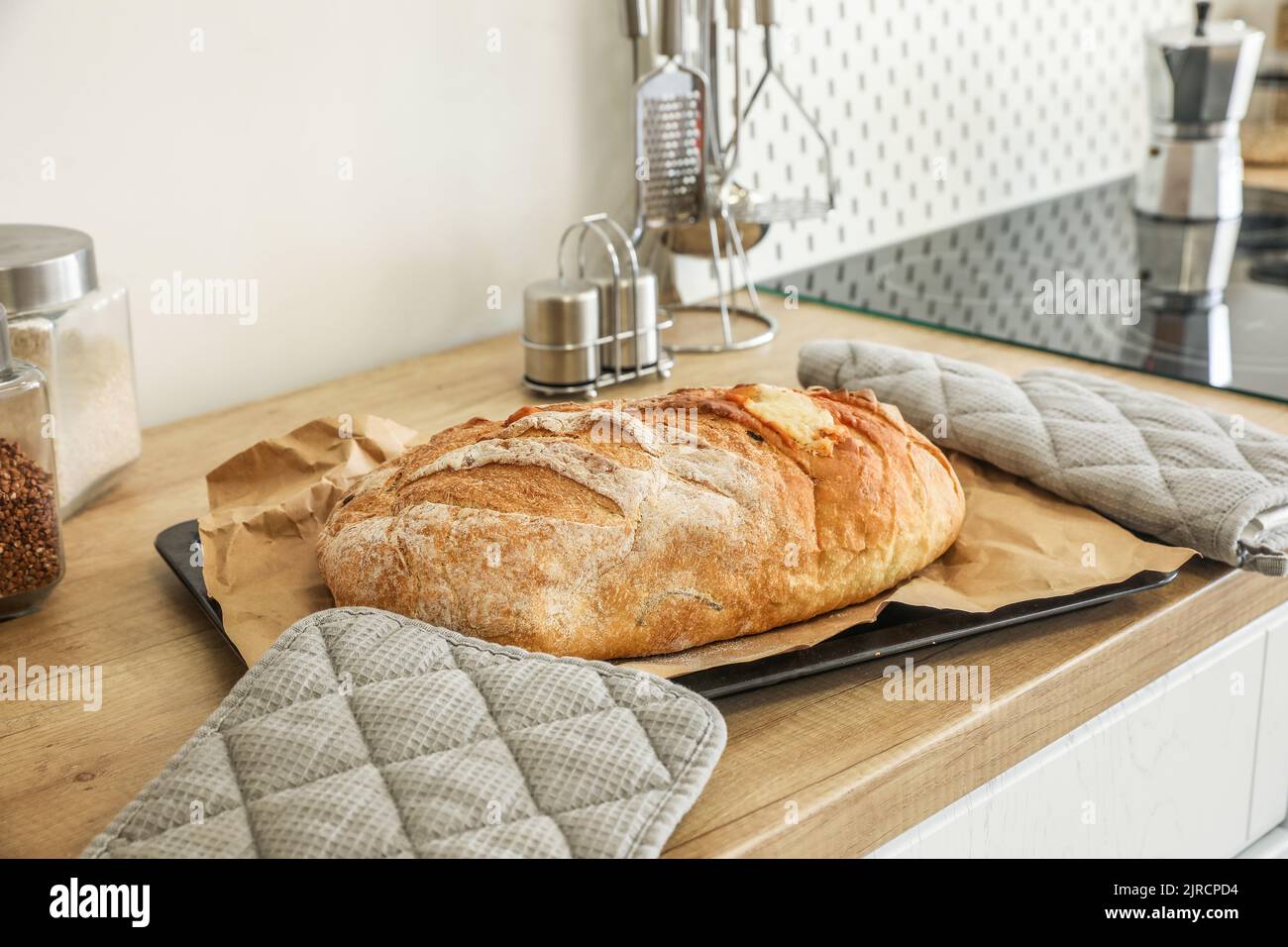 Baking sheet with fresh bread and oven mittens on counter in kitchen ...