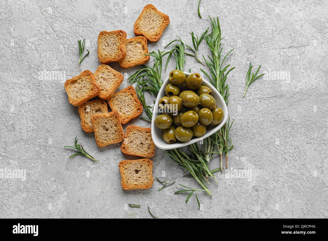 Composition with bowl of tasty green olives, rosemary and crackers on ...
