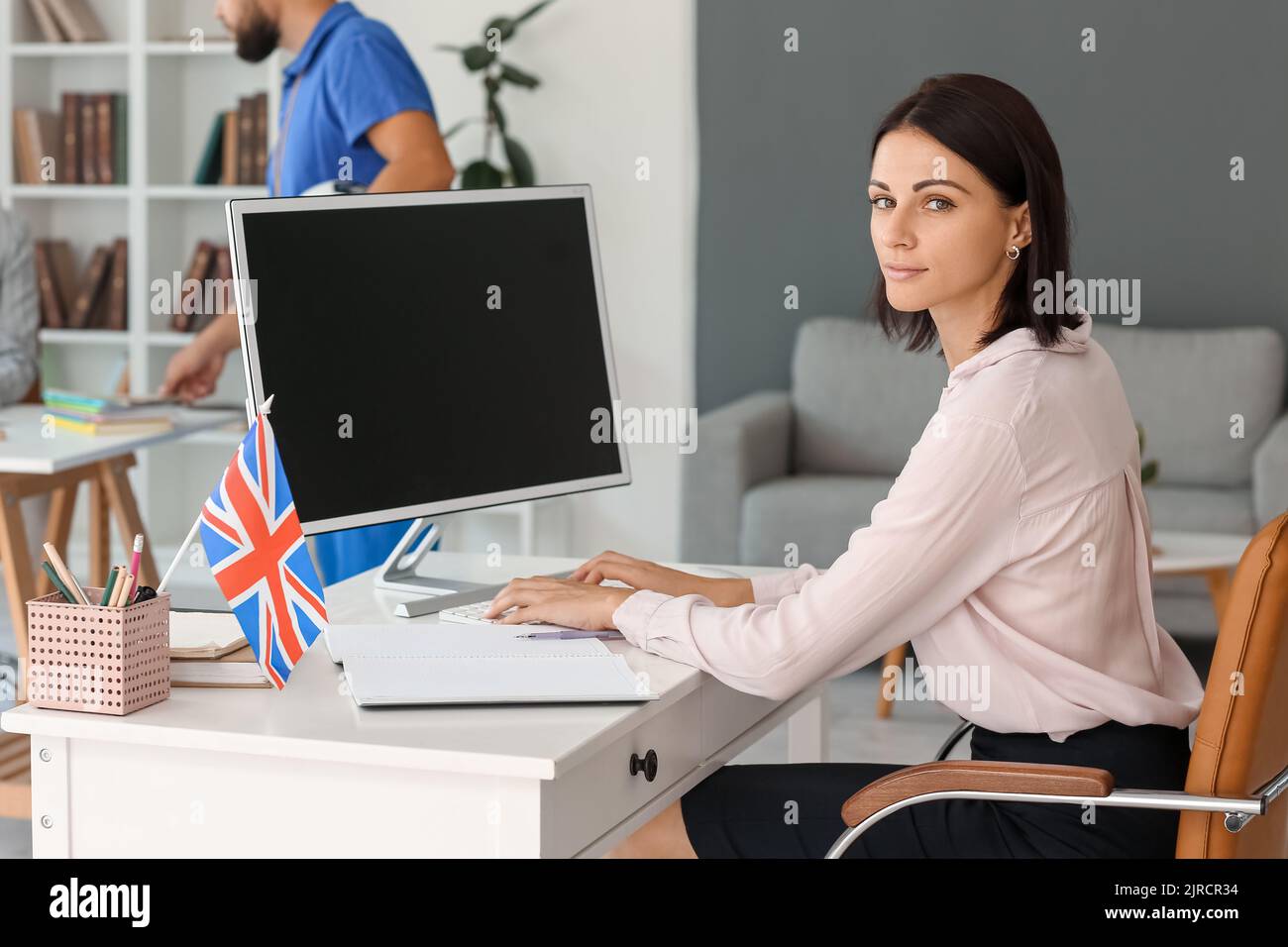 Young English teacher working with computer at table in school Stock ...