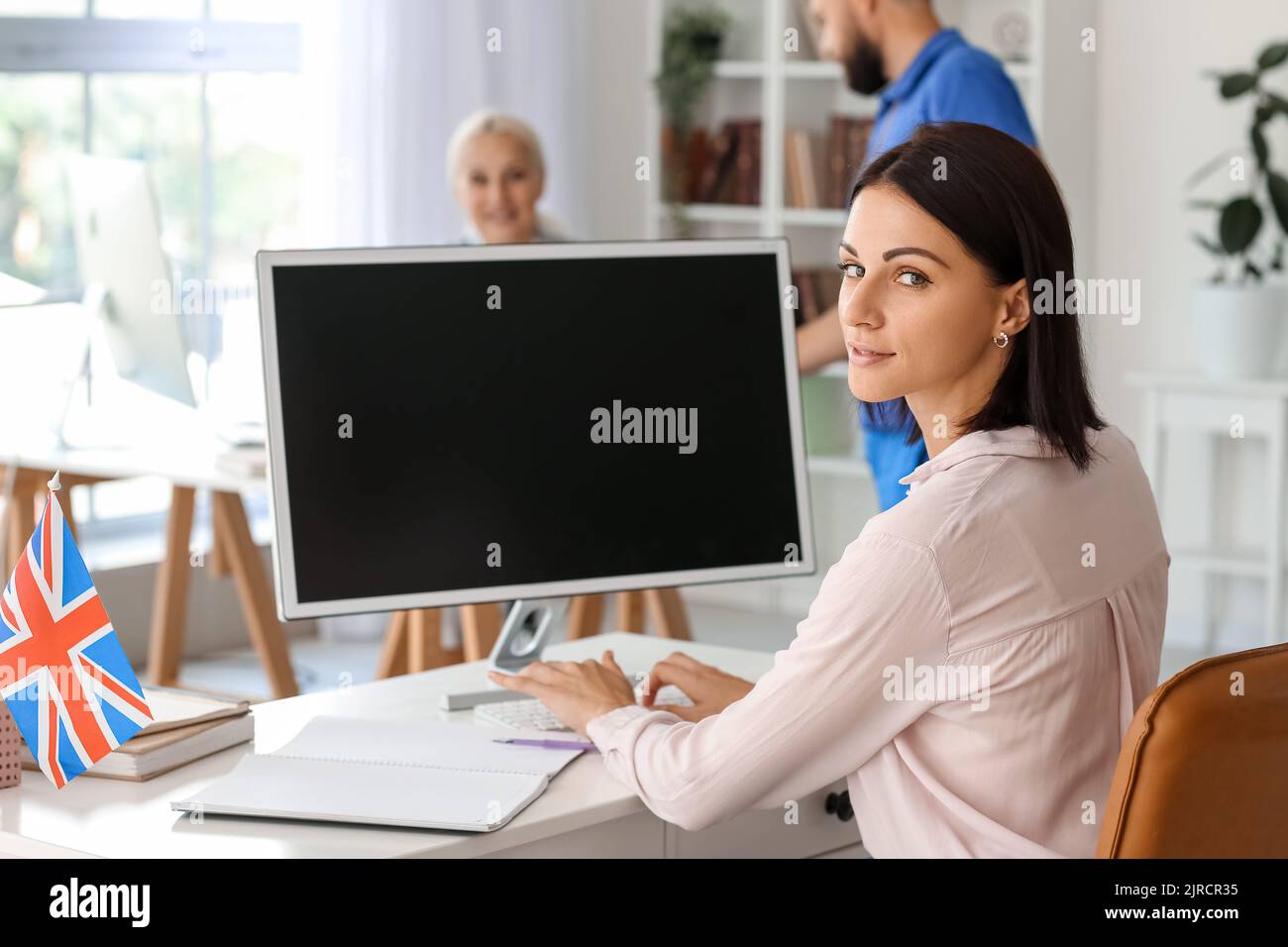 Young English teacher working with computer at table in school Stock ...
