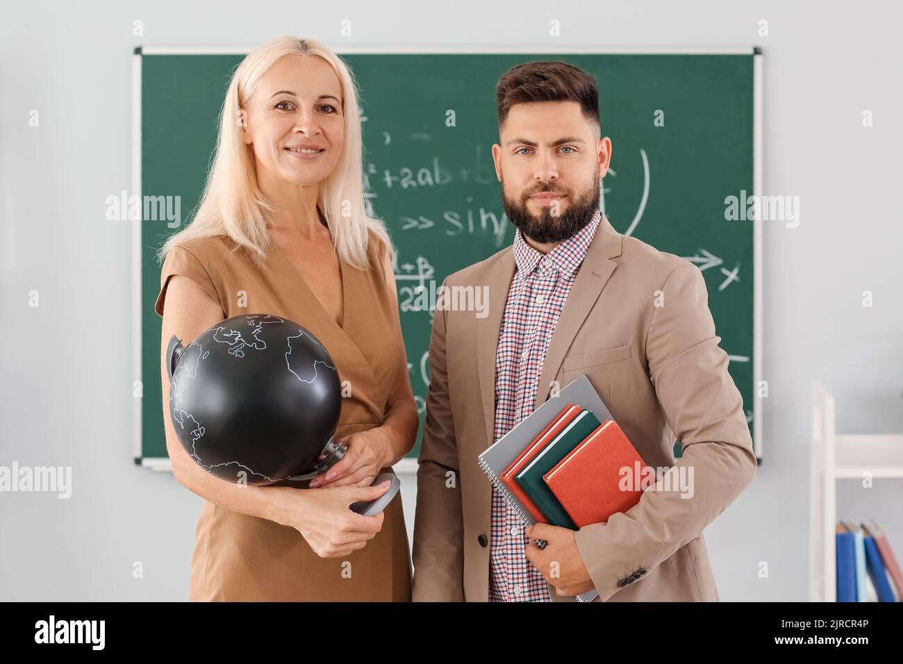 Teachers with globe and books in classroom Stock Photo - Alamy