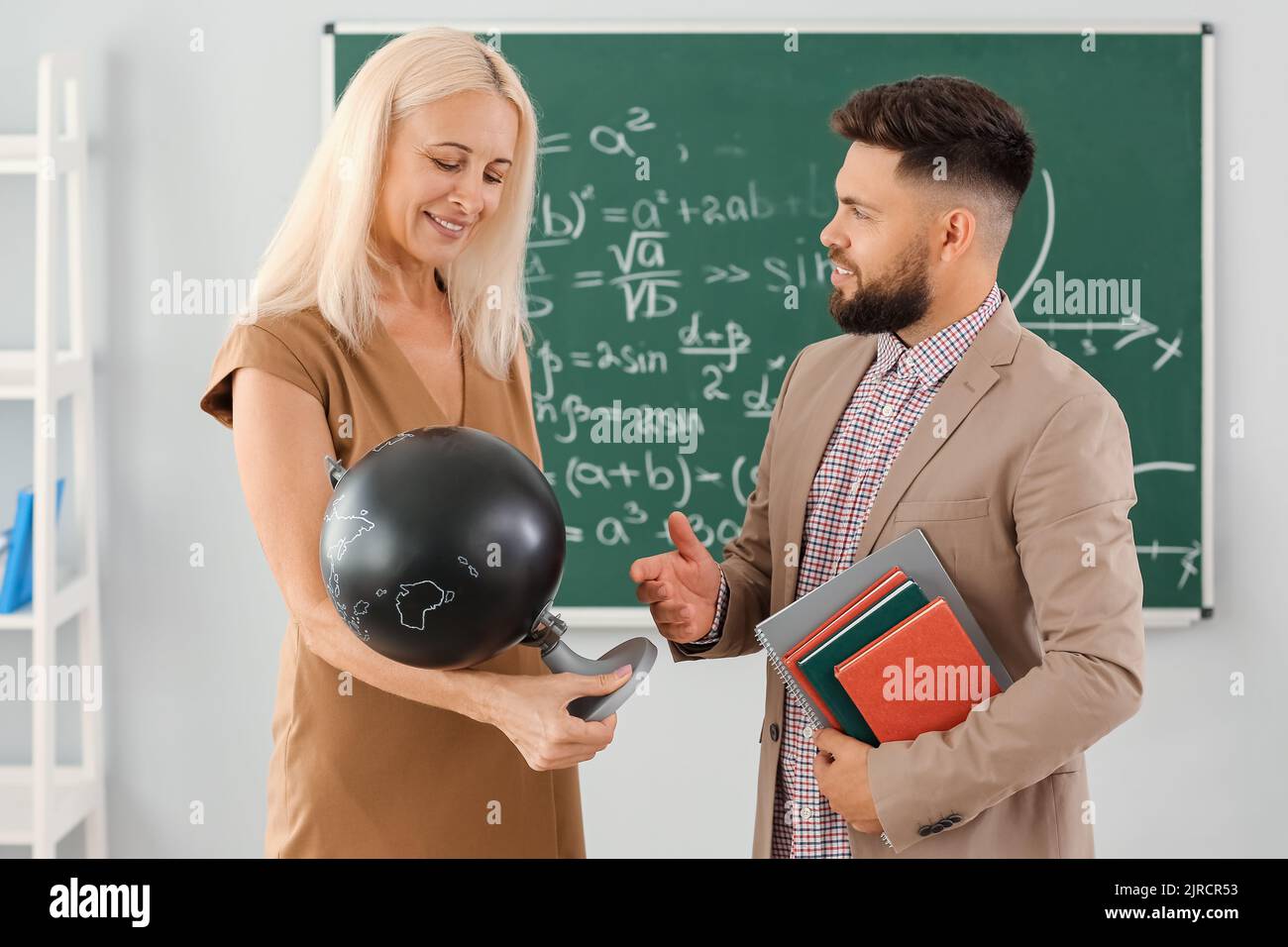 Teachers with globe and books in classroom Stock Photo - Alamy