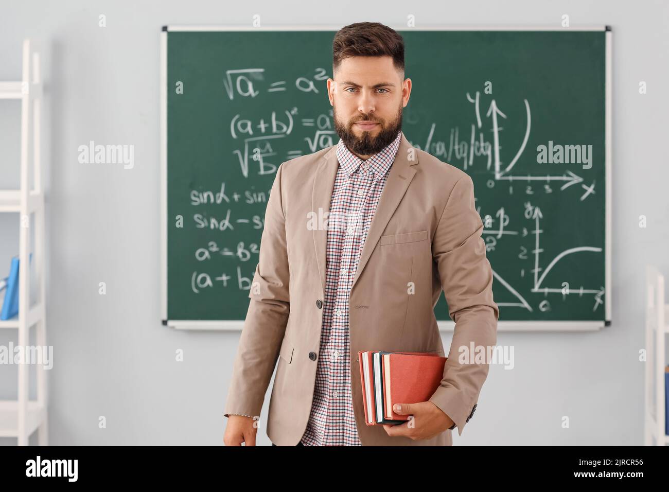 Handsome Math teacher with books in classroom Stock Photo - Alamy