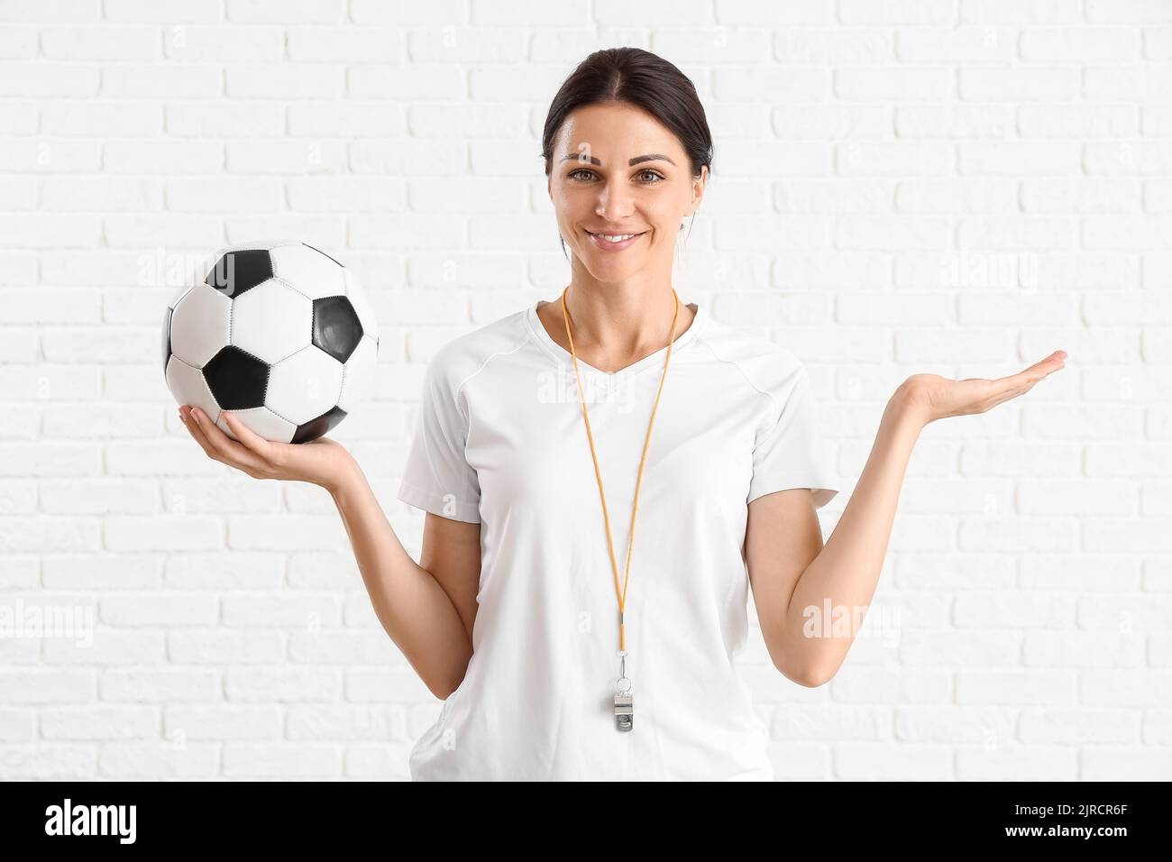 Beautiful PE teacher with ball on white brick background Stock Photo ...