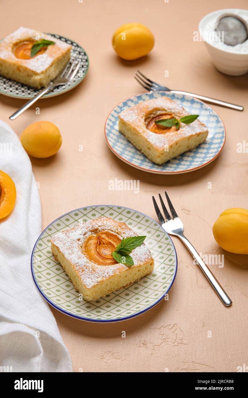 Plates with pieces of delicious apricot pie on color background Stock ...