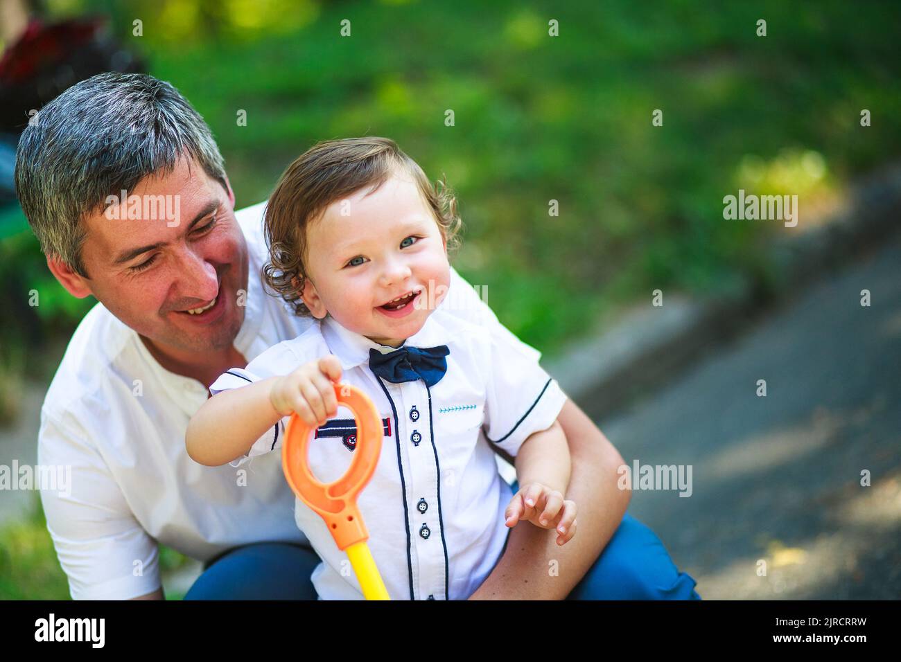 Little beautiful boy in the arms of his father. Todder shirt cling to a ...