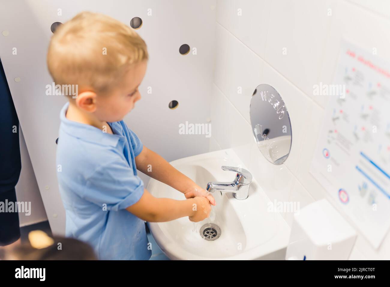 little blond boy washing hands in the bathroom of the nursery. High ...