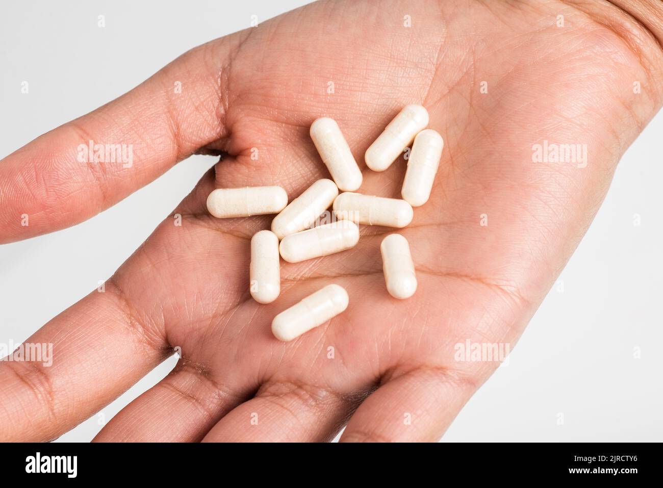 Hand holding vitamin pills, supplements in palm of hand Stock Photo - Alamy