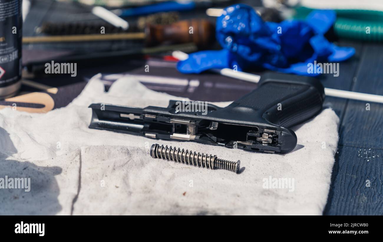 Handgun broken down into parts with exposed barrel at gunsmith workshop ...
