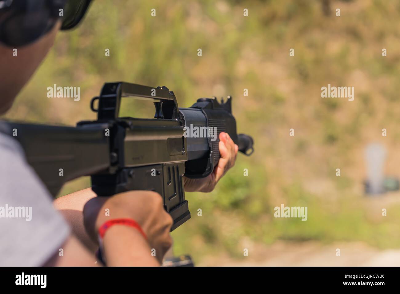Unrecognizable man aiming shotgun practicing on outdoor firing range ...