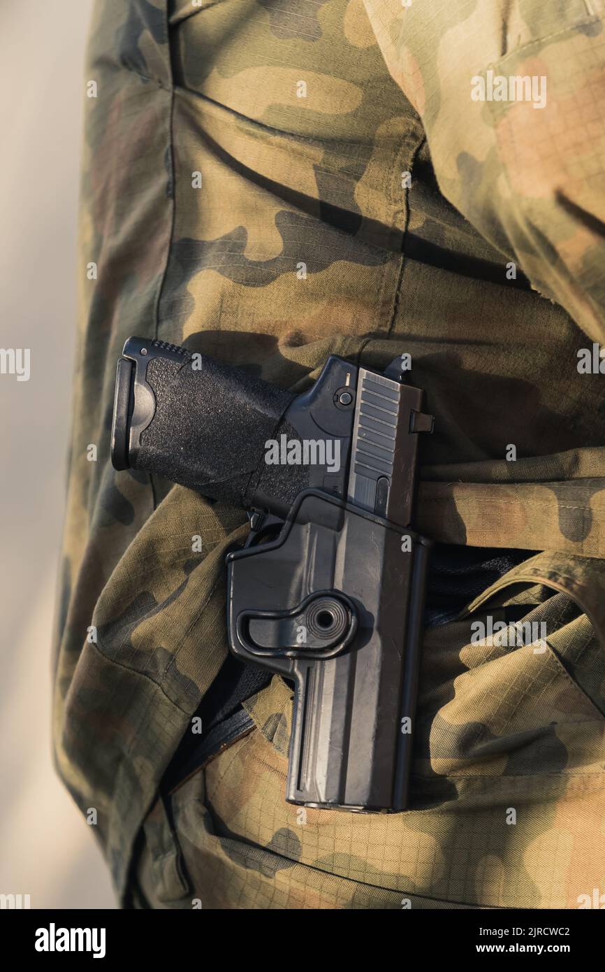 Vertical close-up shot of handgun in holster around soldier's waist ...