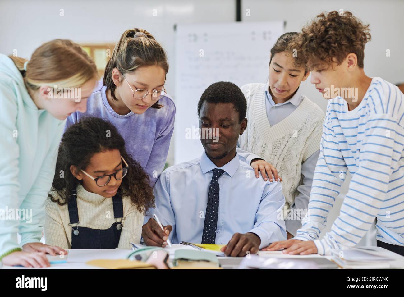 Portrait of young black teacher smiling with diverse group of children ...