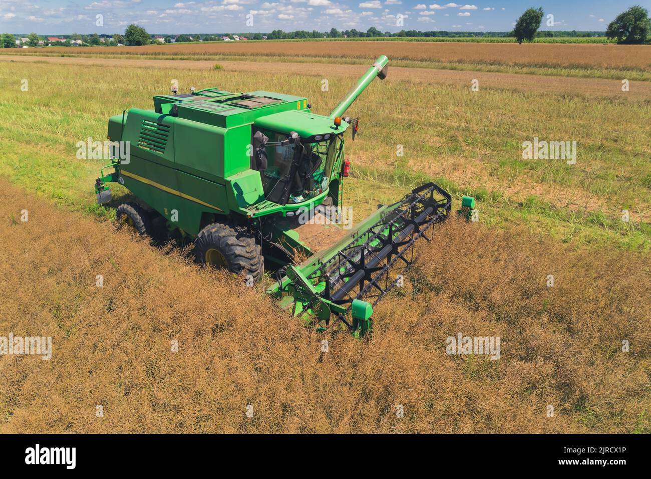 Farmland. Green combine harvester and unrecognizable combine-harvester ...