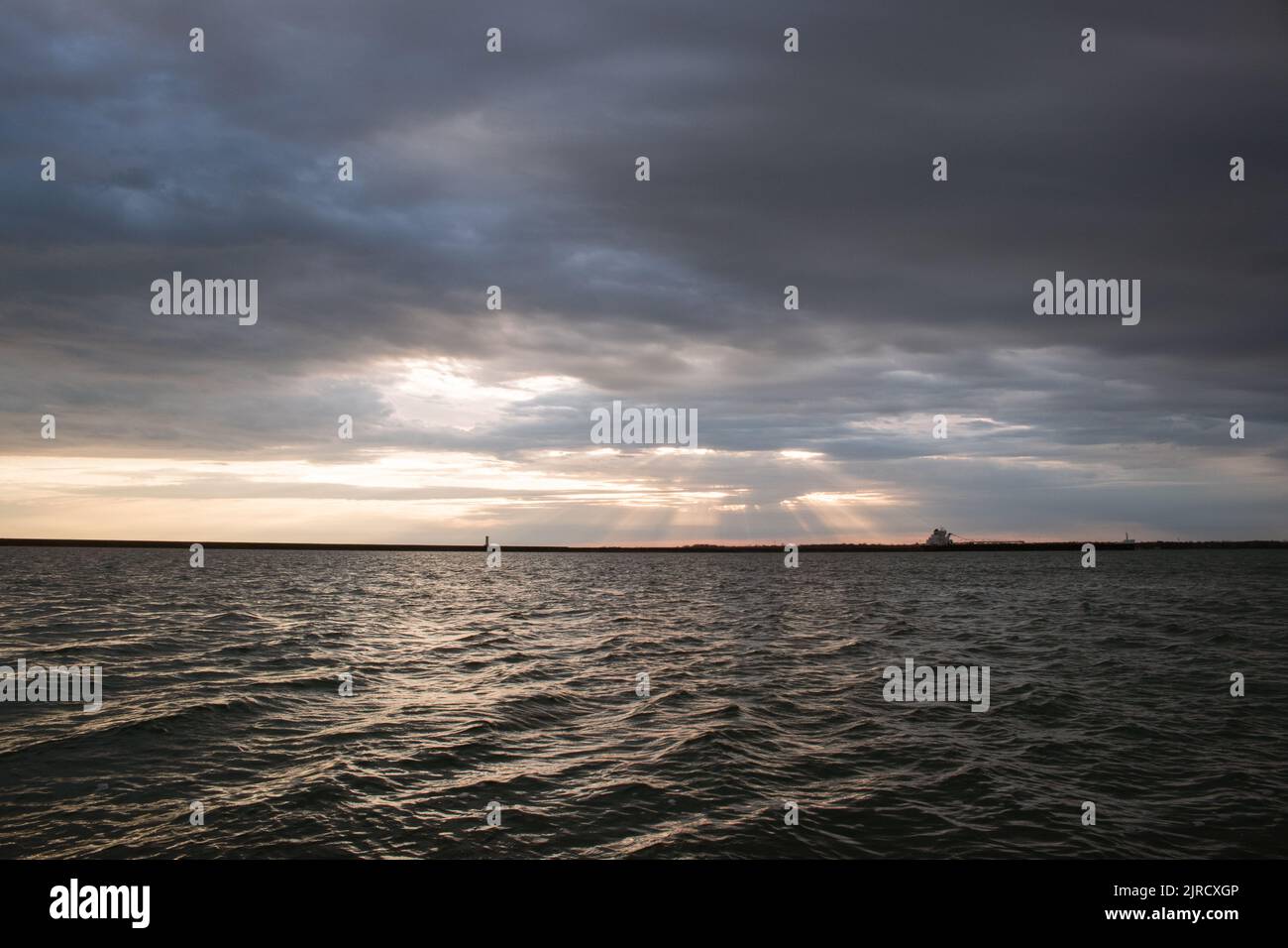 A scenic shot of the calm sea with the evening sun reflection on the ...