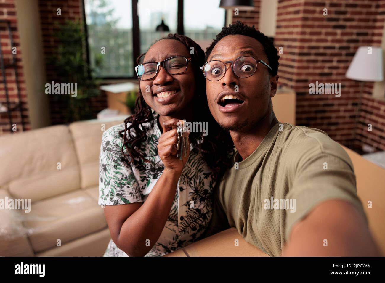 Smiling husband and wife celebrate getting house keys after buying property on mortgage loan ...