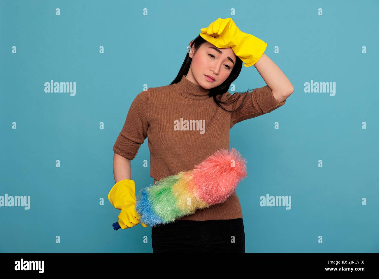 Tired depressed and overworked asian woman holding colorful duster ...