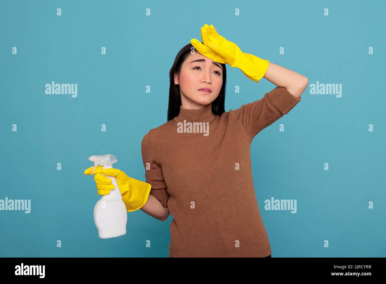 Exhausted asian housekeeper stressed and angry from chores, holding ...