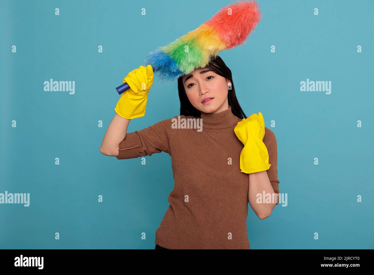 Asian housekeeper stressed and angry from chores holding colorful ...