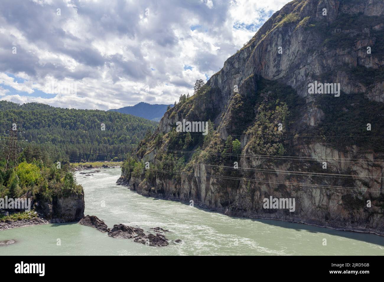 A fast-flowing wide and full-flowing mountain river. Large rocks stick ...