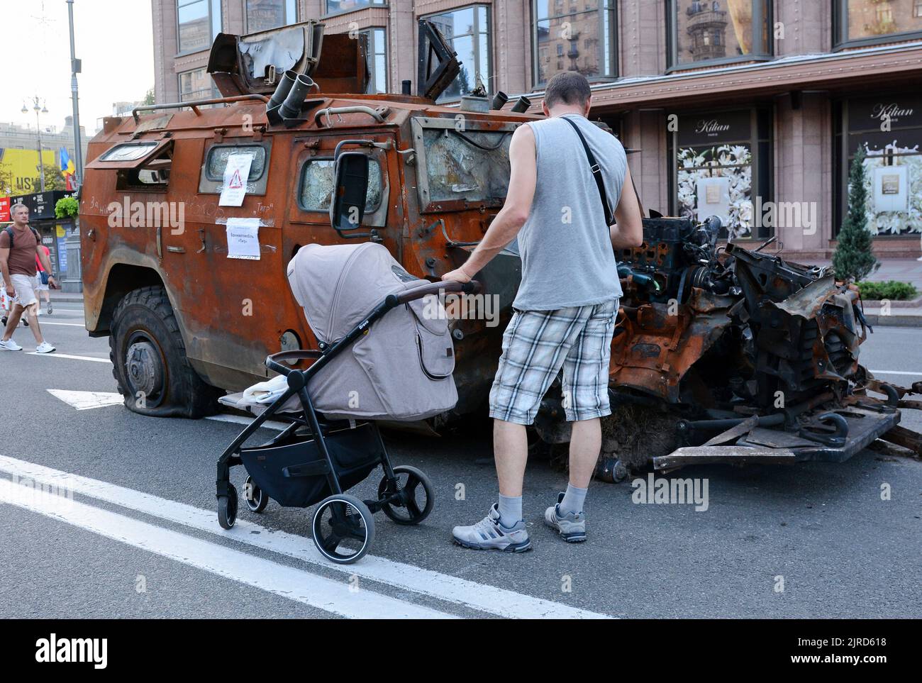 A man with a child in a stroller observes a destroyed Russian army ...