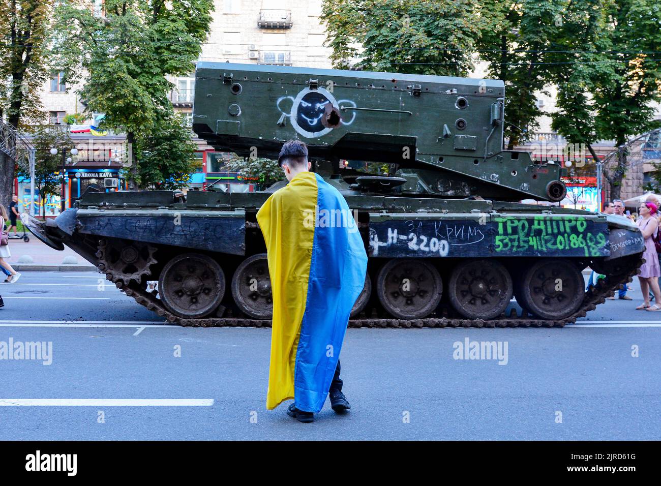 A guy wrapped in the flag of Ukraine examines the destroyed equipment ...