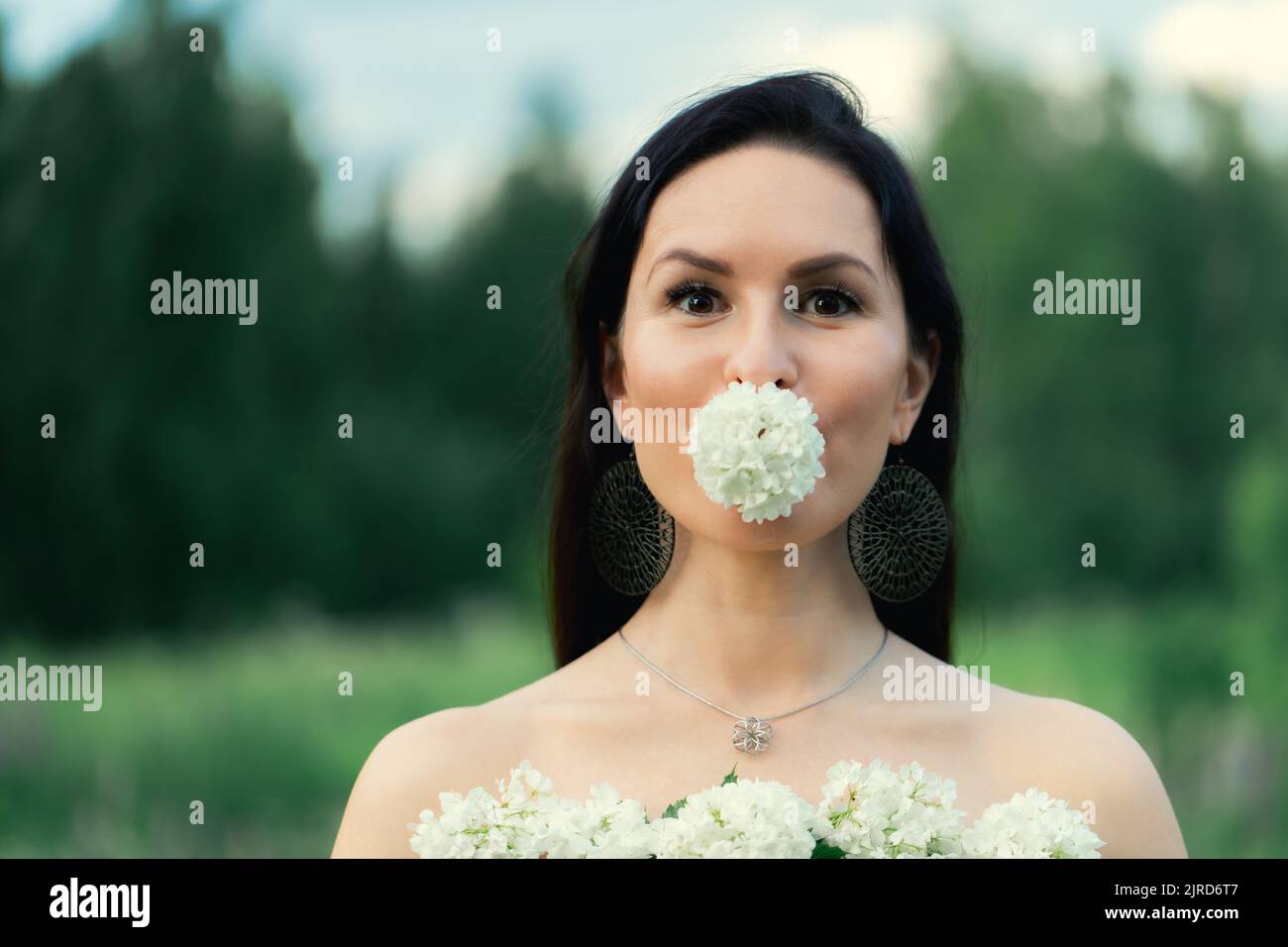 Portrait of an attractive woman with a Viburnum flower in her lips ...