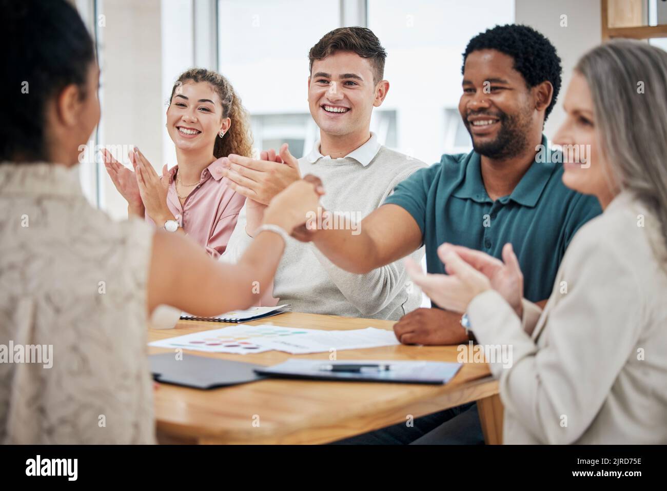 Creative team in meeting clapping and giving a handshake for a ...