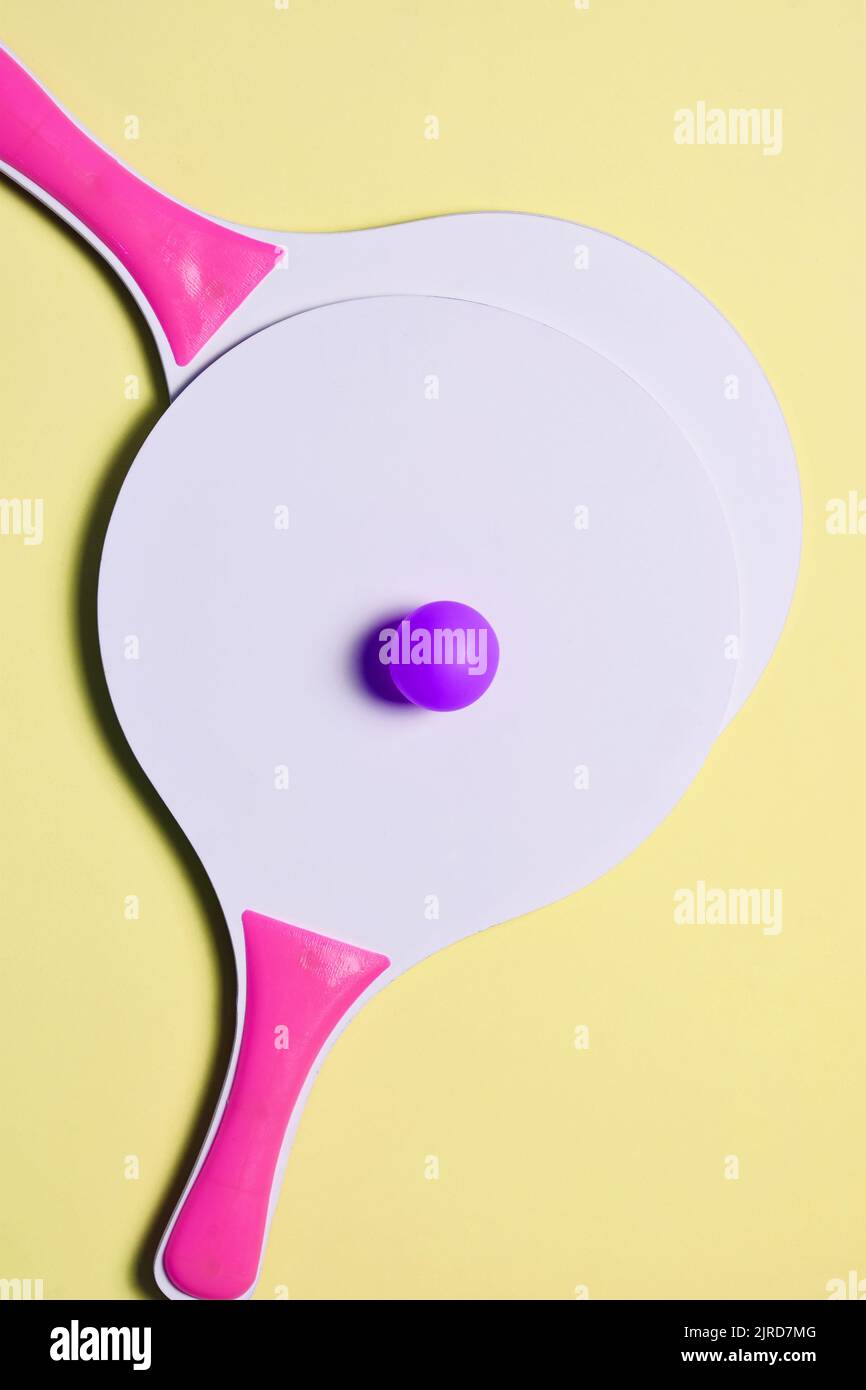Two beach tennis rackets with a ball on a light yellow background Stock ...