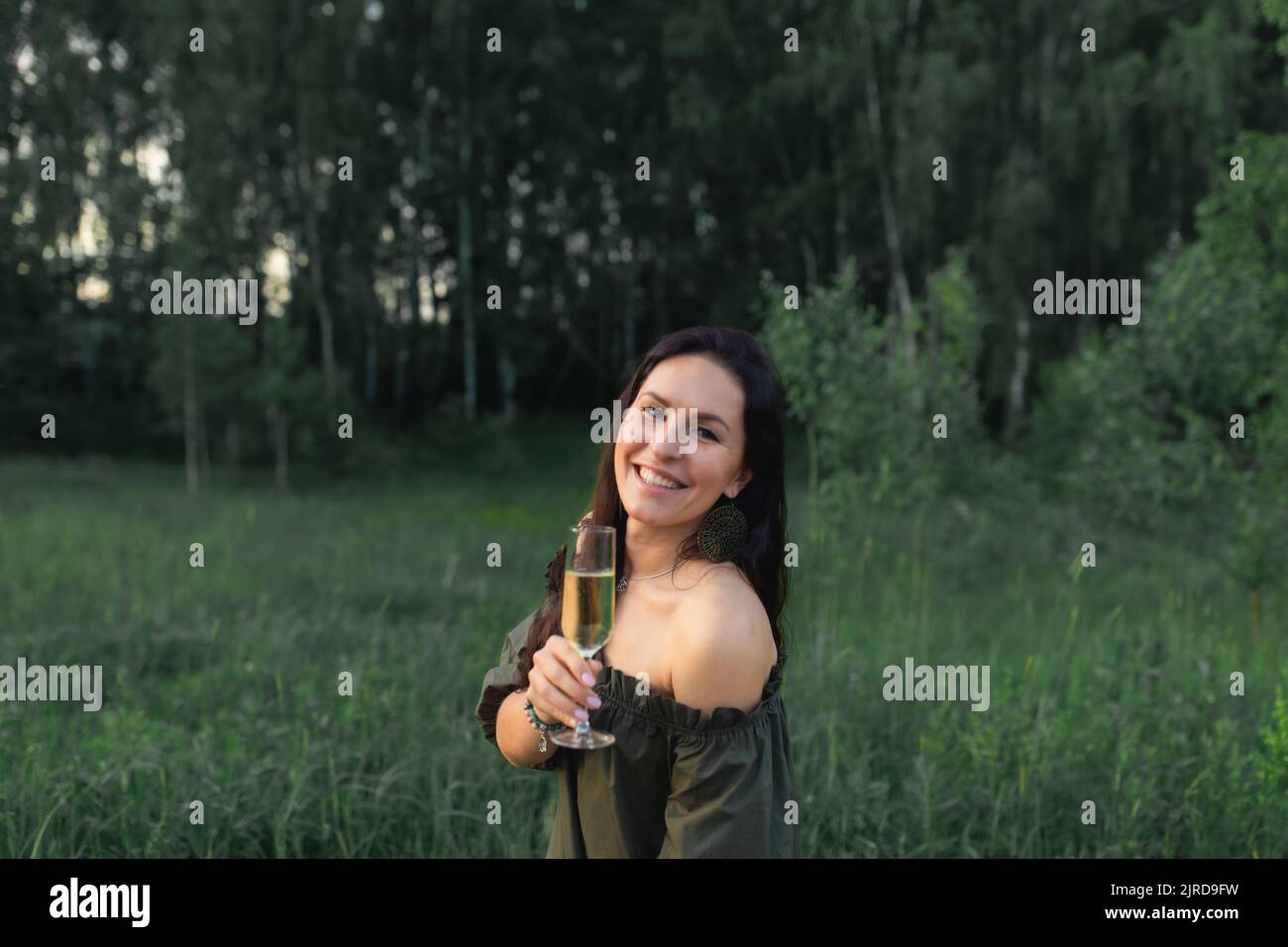 An attractive woman with a glass of champagne on a forest plot in the ...