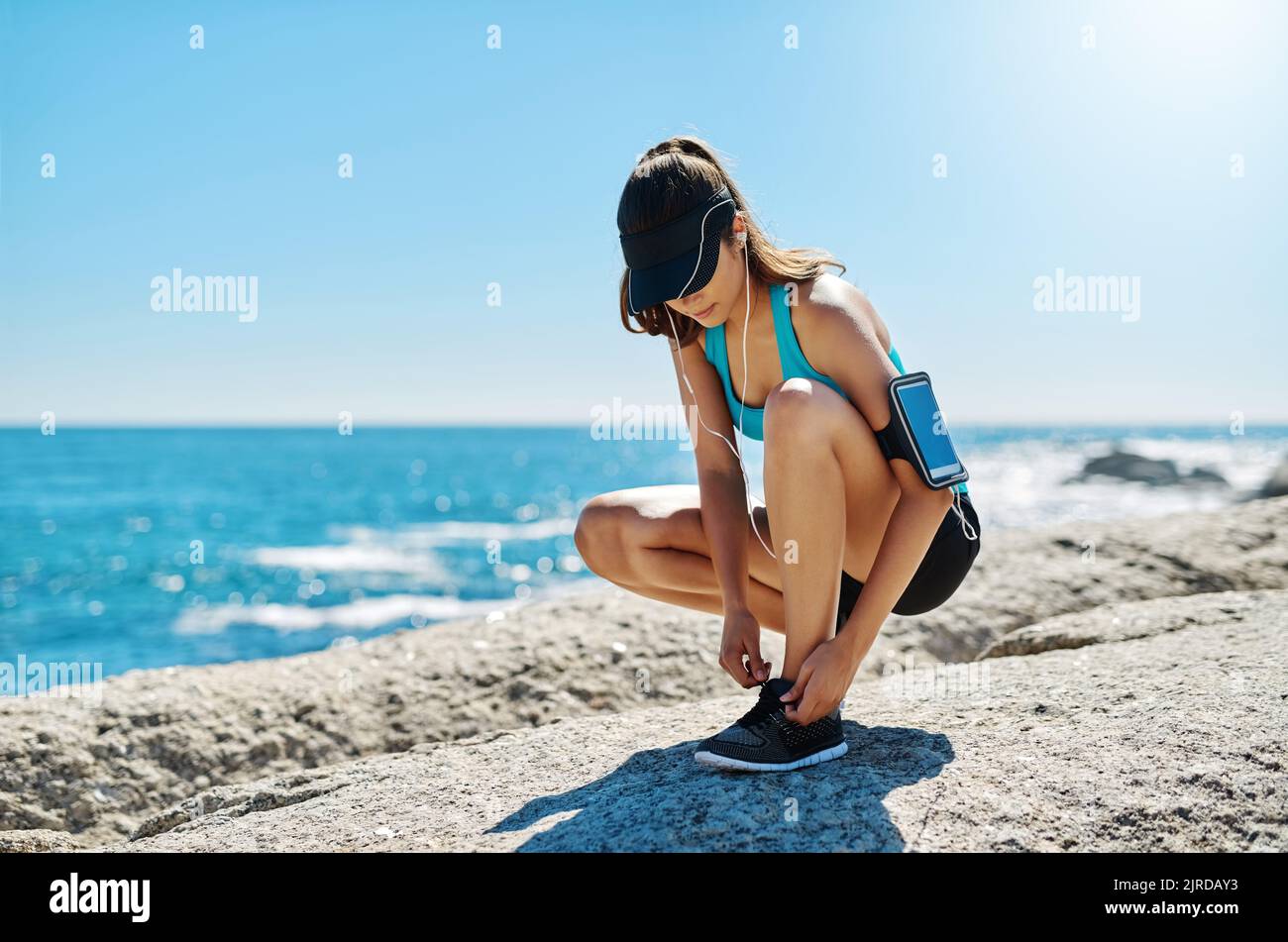 This princess wears running shoes. a sporty young woman tying her shoelaces while out for a run ...