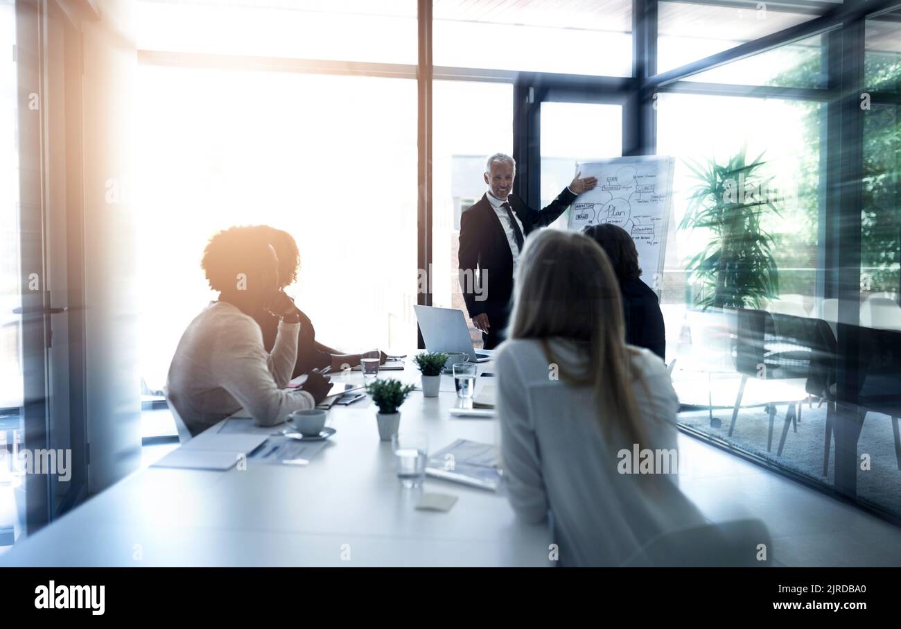Guiding his team to success. a mature businessman giving a presentation ...