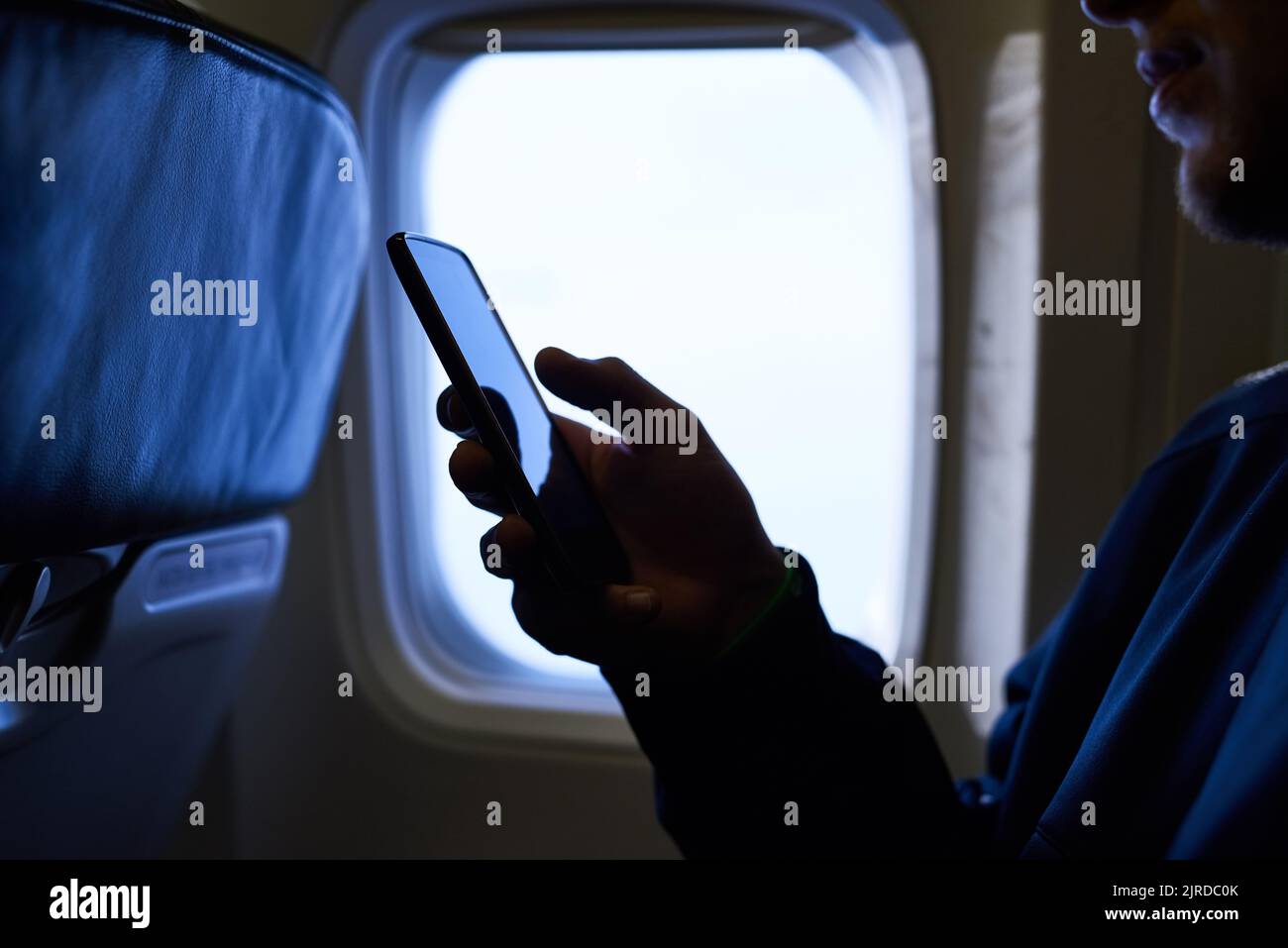Switching his phone to airplane mode. an unidentifiable passenger using ...