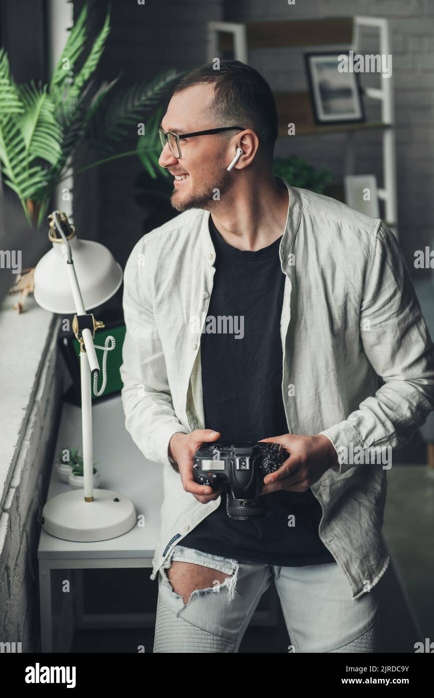 Handsome young man with a professional camera standing in his office ...