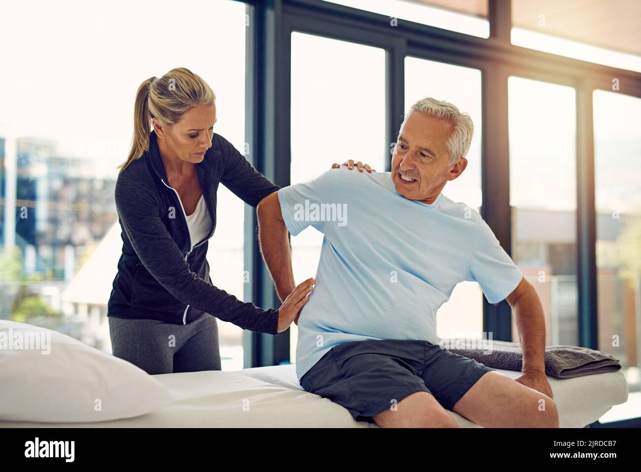 Examining the problem area. a physiotherapist examining a senior ...