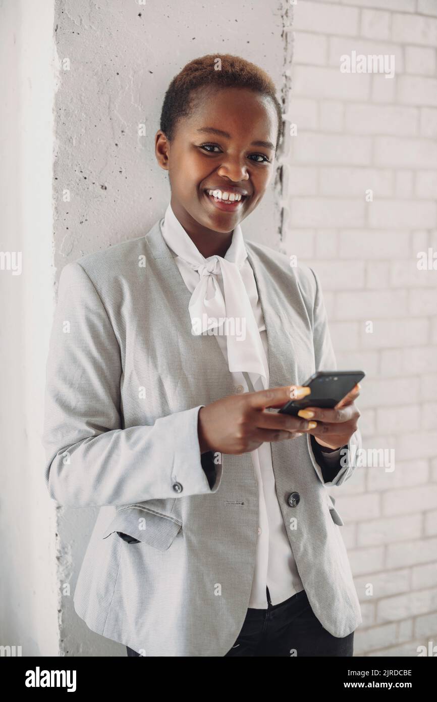 Beautiful smiling businesswoman standing in a business office and using ...