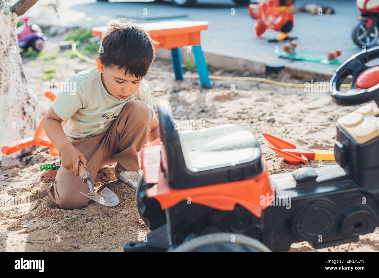 Boy playing digging in the sand in the garden during the summer ...