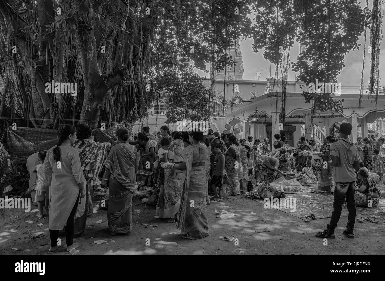 A group of Hindu people gathered around a banyan tree in a temple to ...