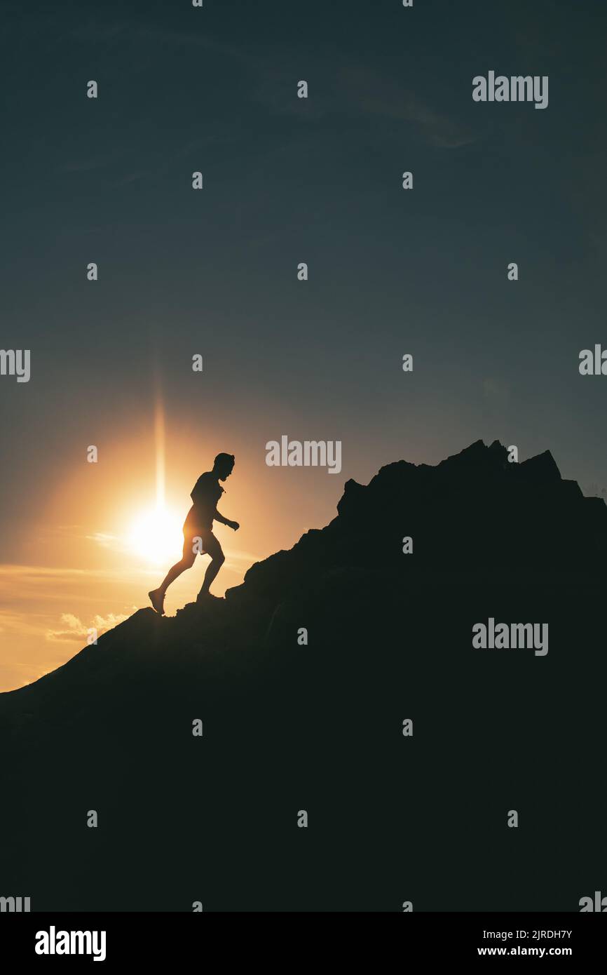 A colorful mountain sunset with a man running through the rocks of a ...