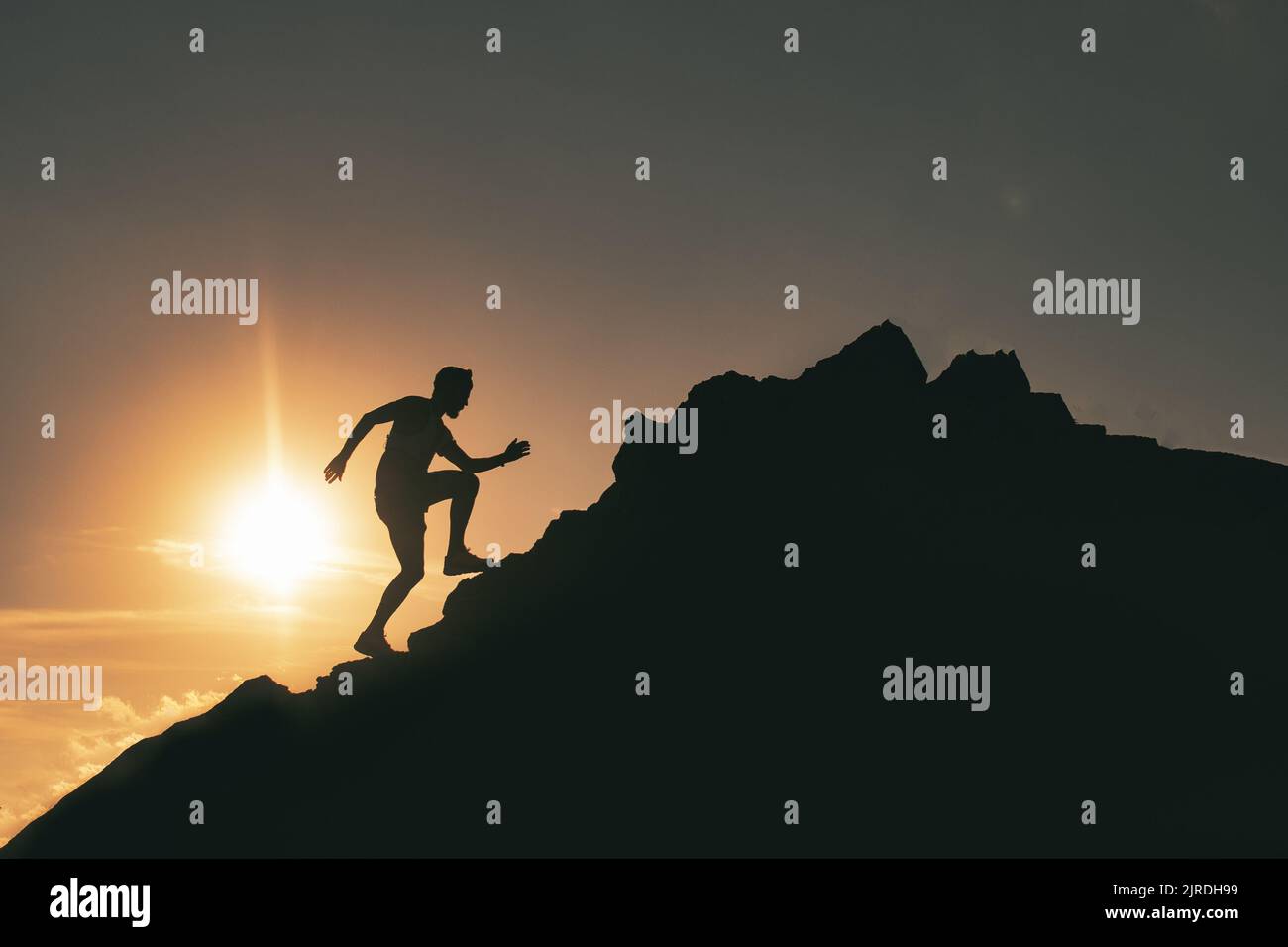 A colorful mountain sunset with a man running through the rocks of a ...