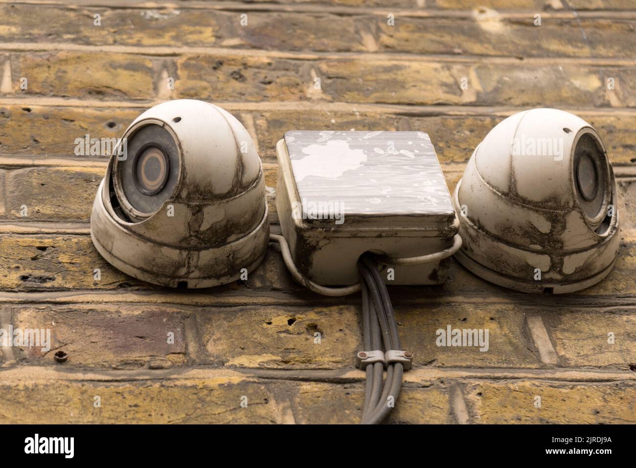 Close up of two mounted on facade dirty white surveillance ccd cameras ...