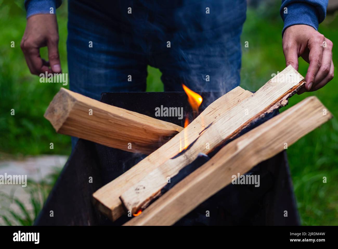 Man throws firewood into brazier. Starting campfire in firepit with ...