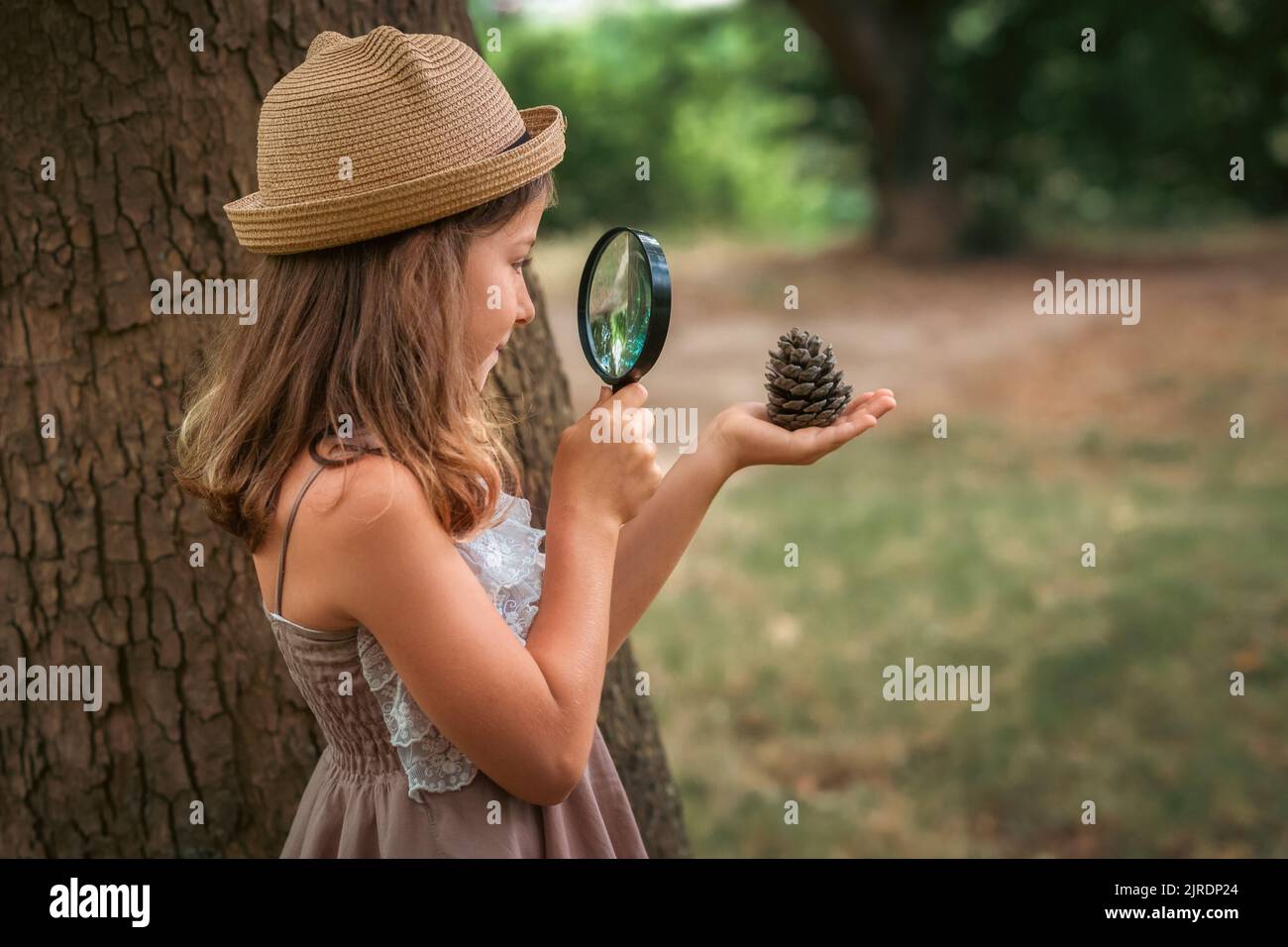Children's education. Pretty little girl scout in a straw hat looks at ...