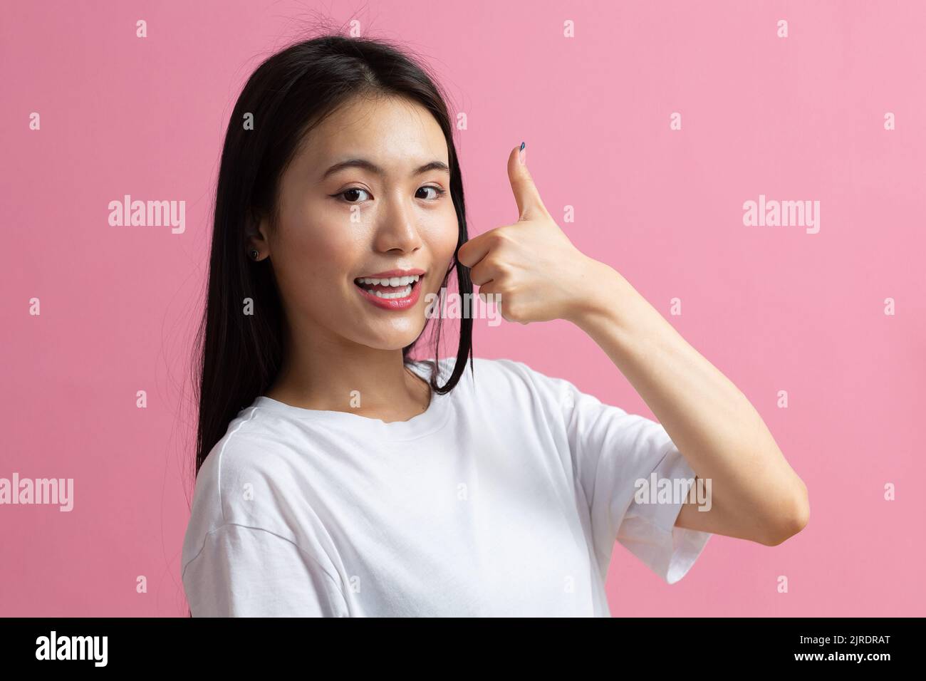 Portrait of asian woman with thumbs up finger on pink background Stock ...