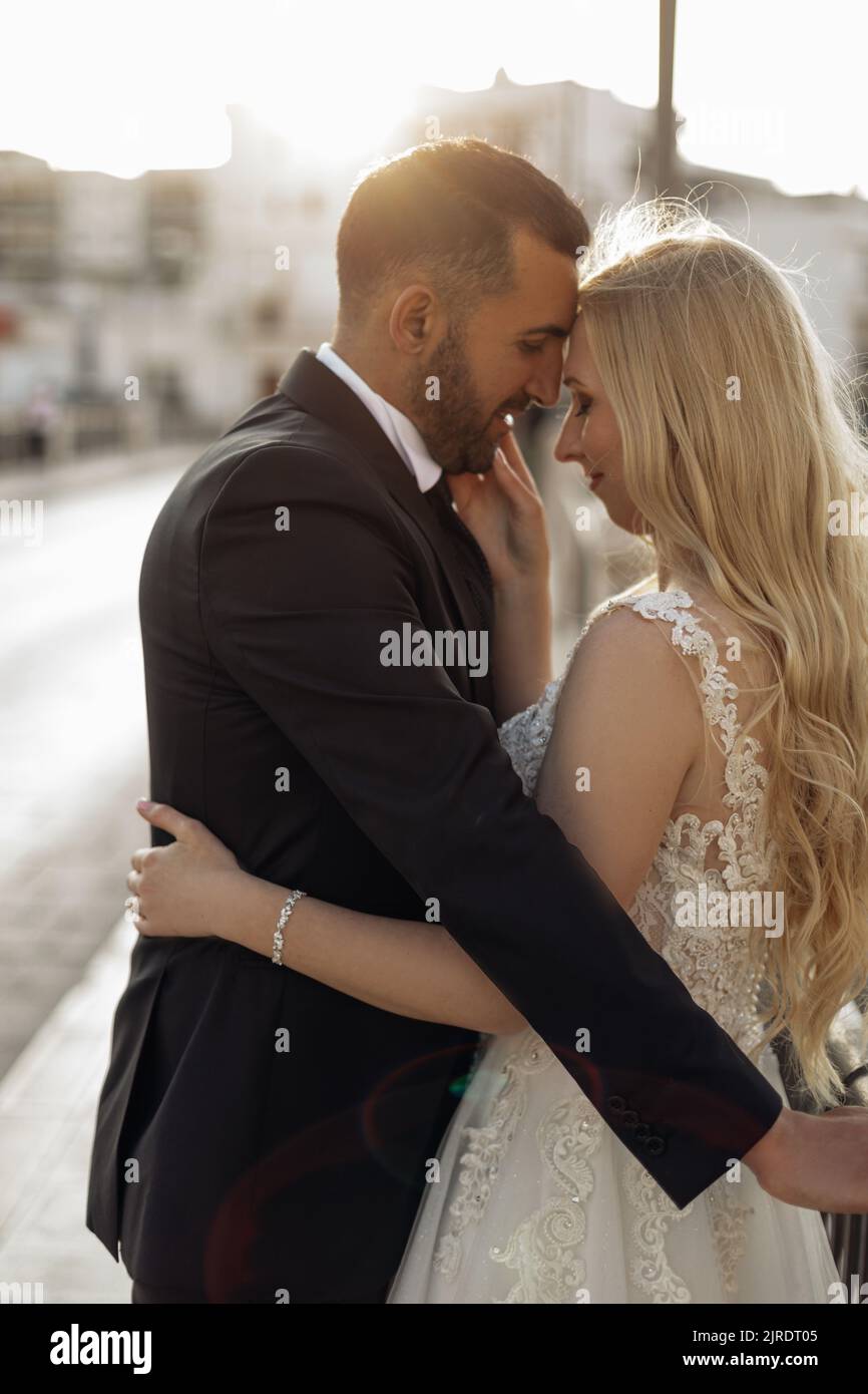 Side view of cute wedding couple standing on street with closed eyes ...