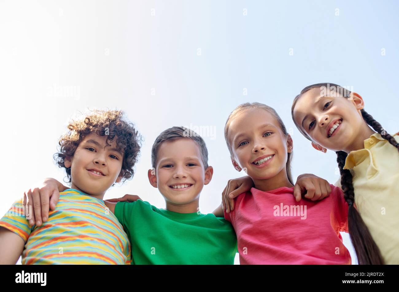 Four friends standing hugging each other in fresh air Stock Photo - Alamy