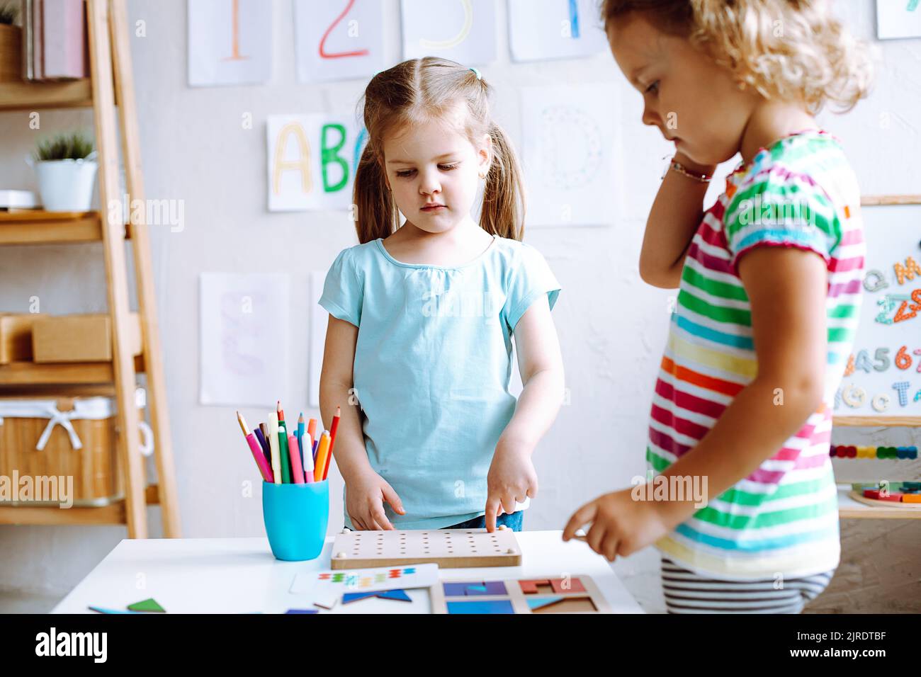 Two concentrated cute little girls children pupils standing at white ...
