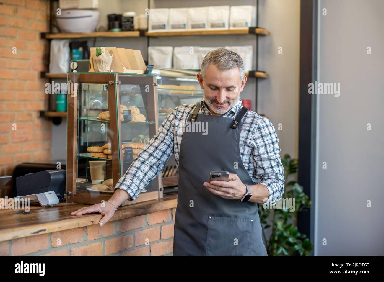 Cafe owner standing near the counter and looking contented Stock Photo ...