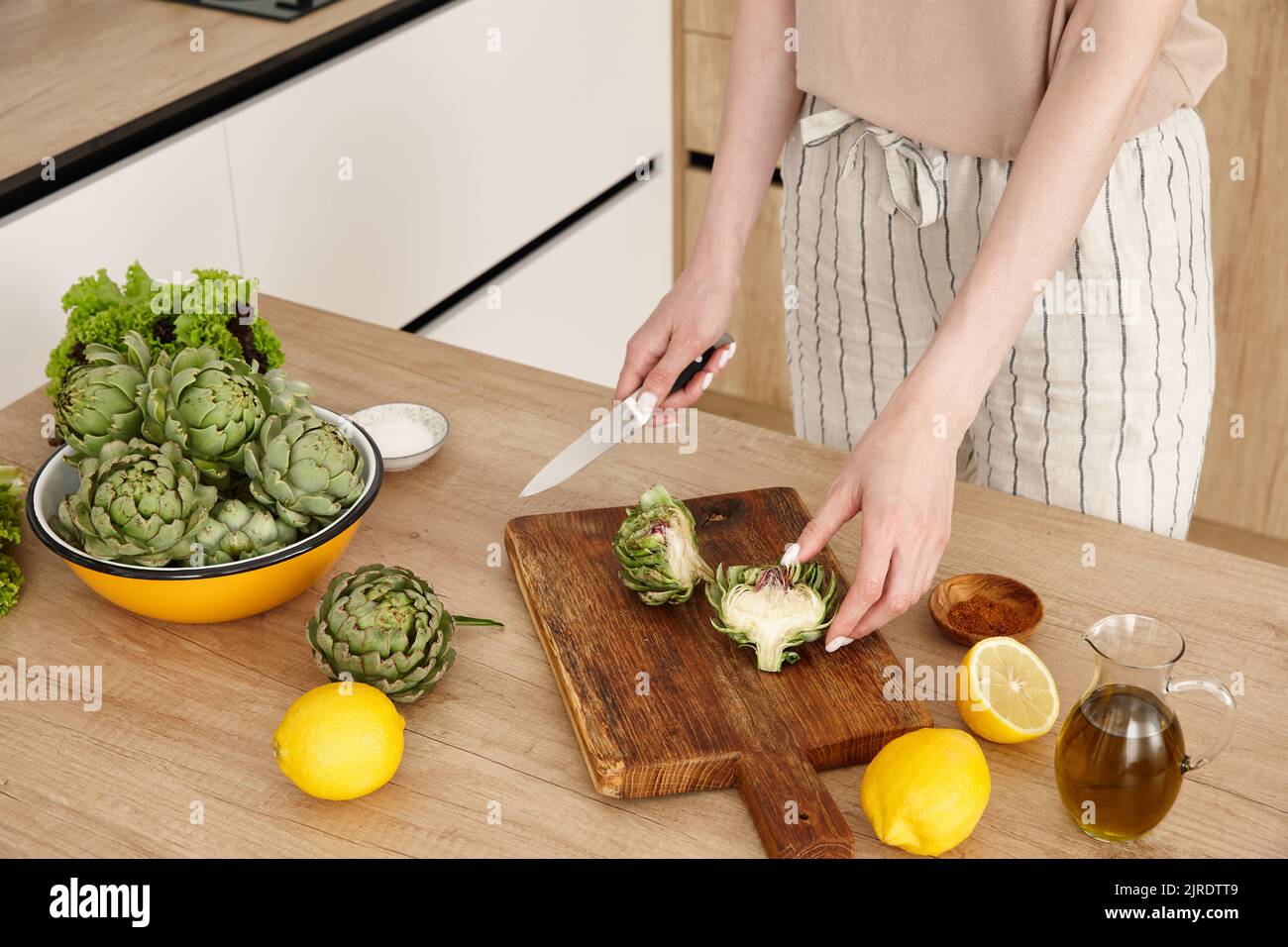 Woman cooking green artichokes in the kitchen Stock Photo - Alamy