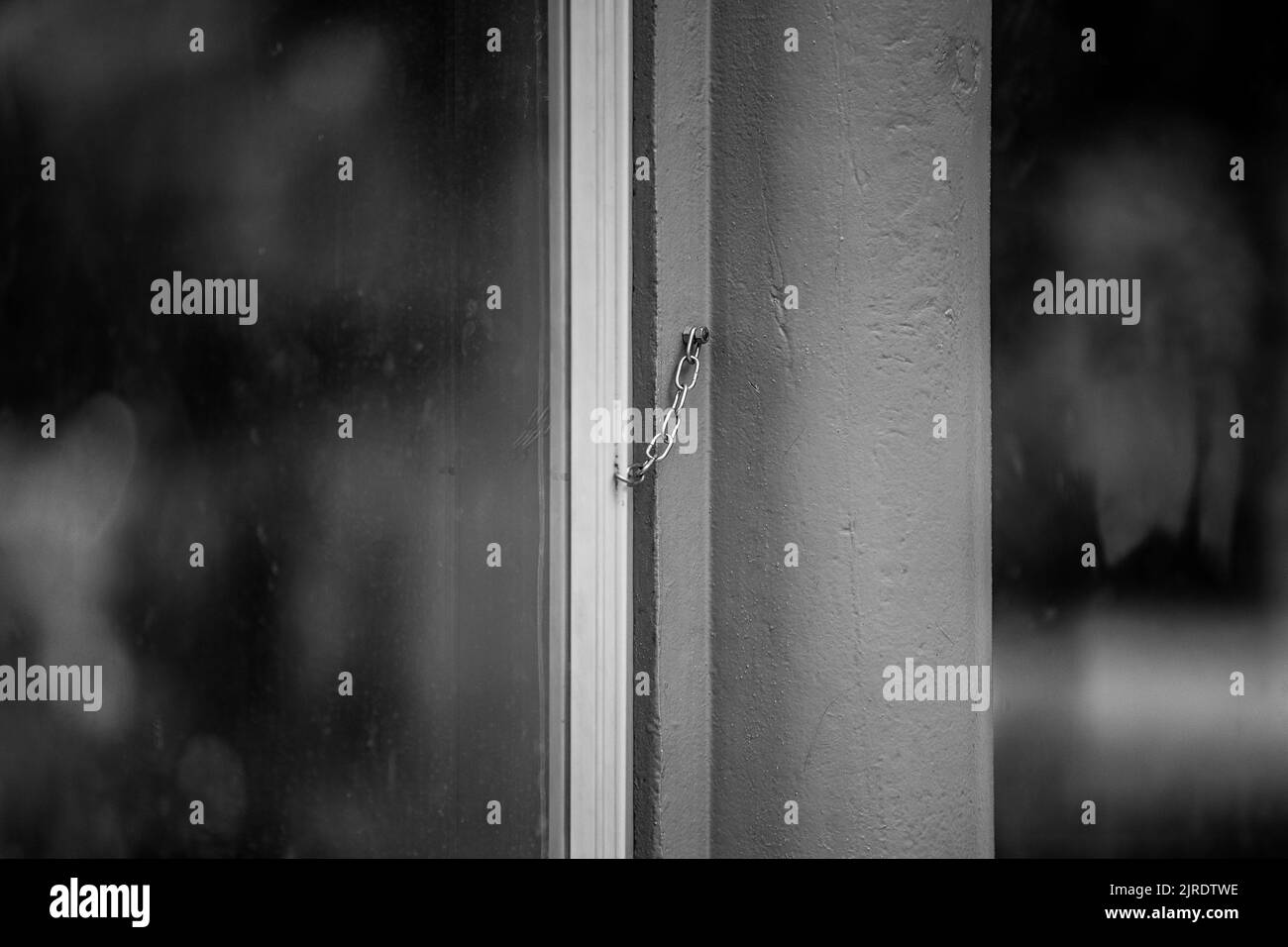 A closeup grayscale shot of a closed window with a chain lock Stock ...