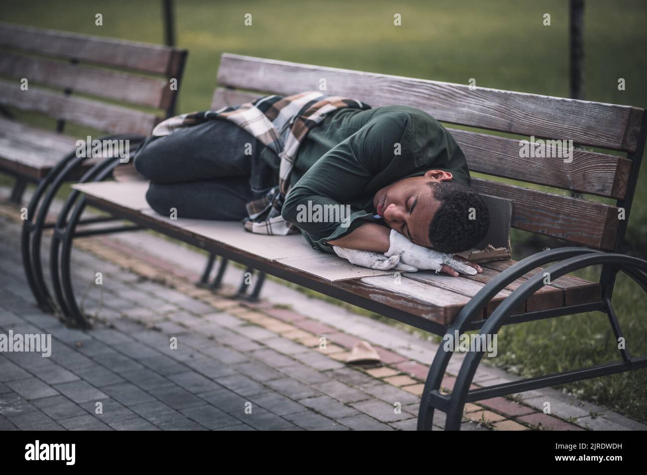 Dark-skinned man lying on park bench Stock Photo - Alamy